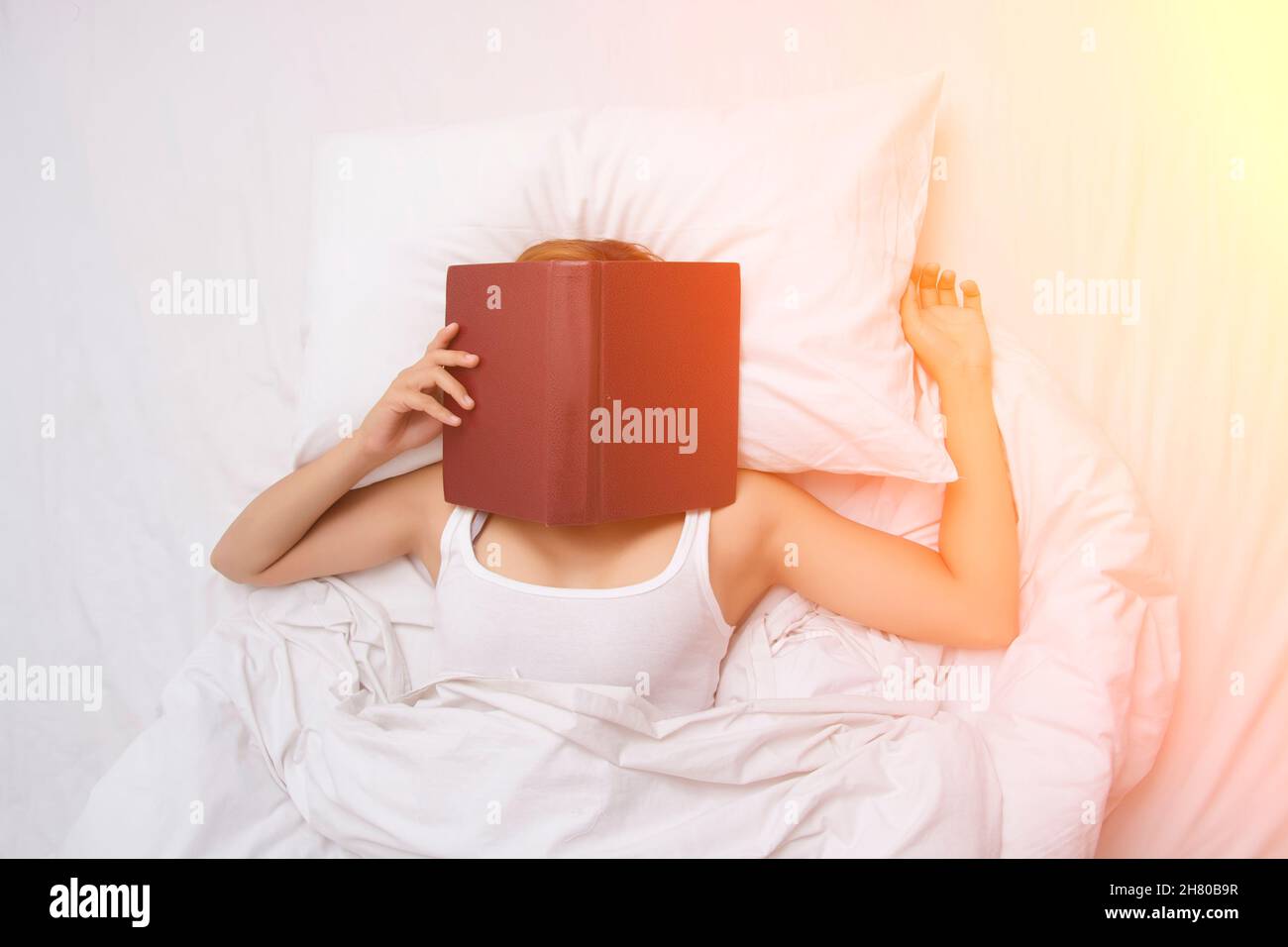 Beautiful young woman sleeping on the bed after read a book with face ...