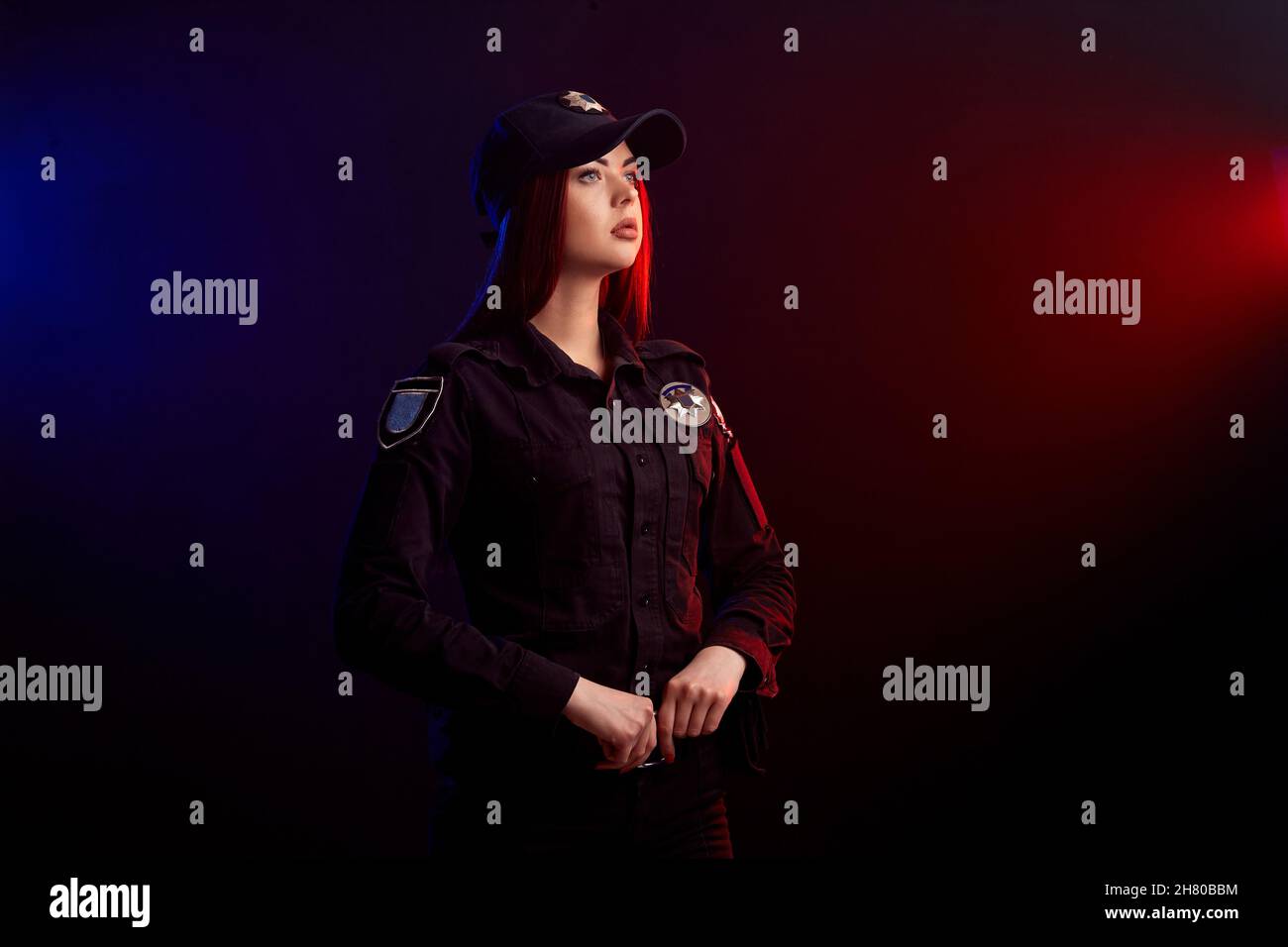 Serious female police officer is posing for the camera against a black ...