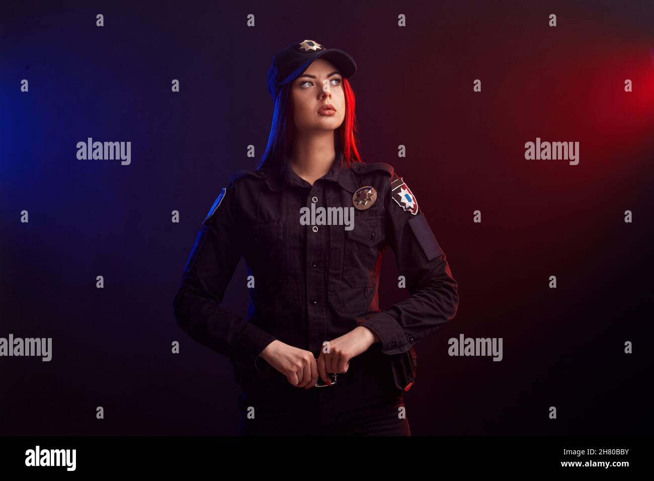 Serious female police officer is posing for the camera against a black ...
