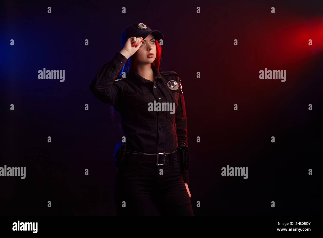 Serious female police officer is posing for the camera against a black ...