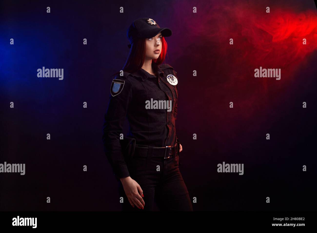 Serious female police officer is posing for the camera against a black ...