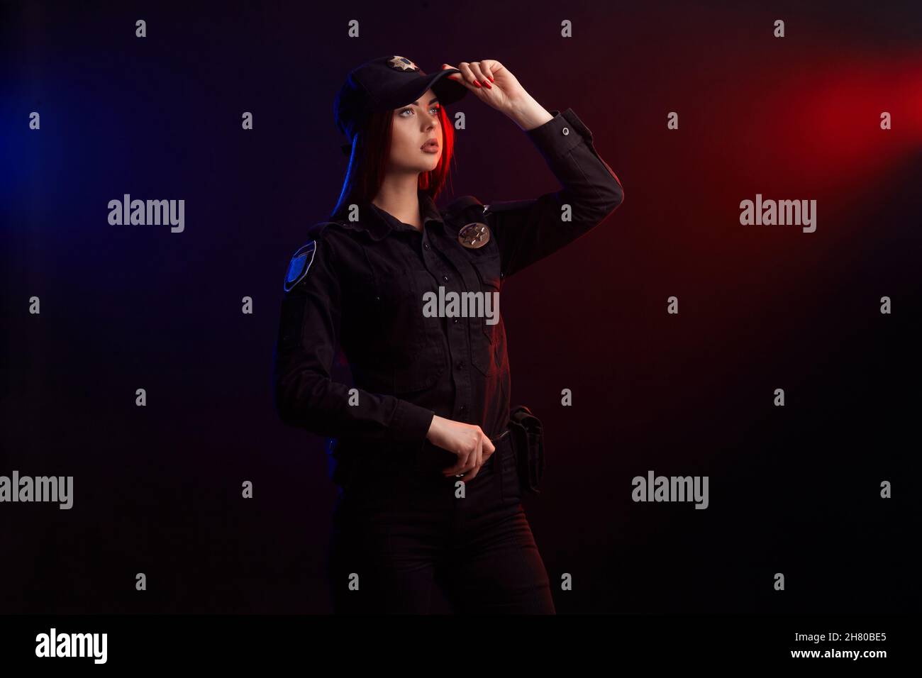Serious female police officer is posing for the camera against a black ...