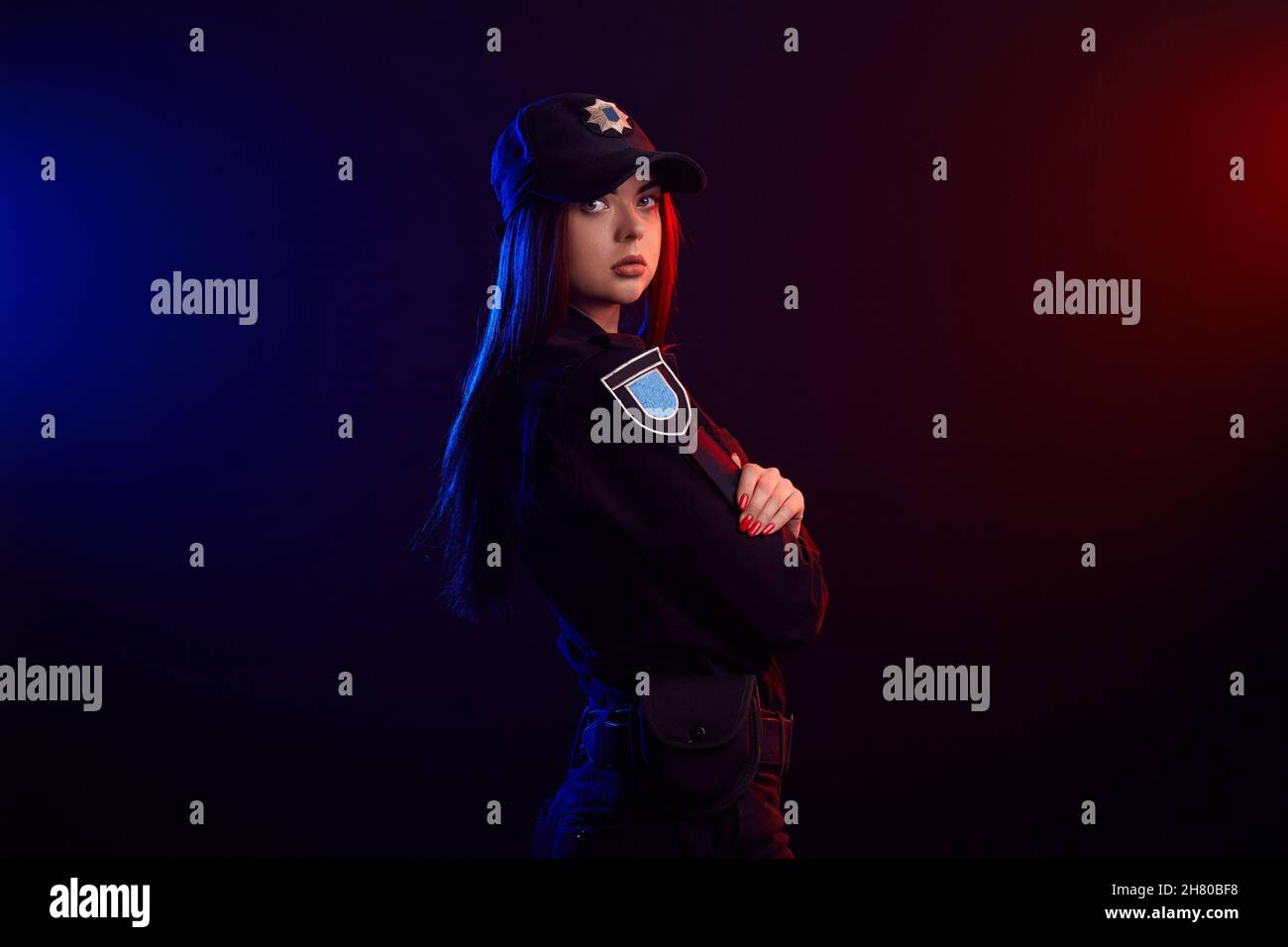 Serious female police officer is posing for the camera against a black ...