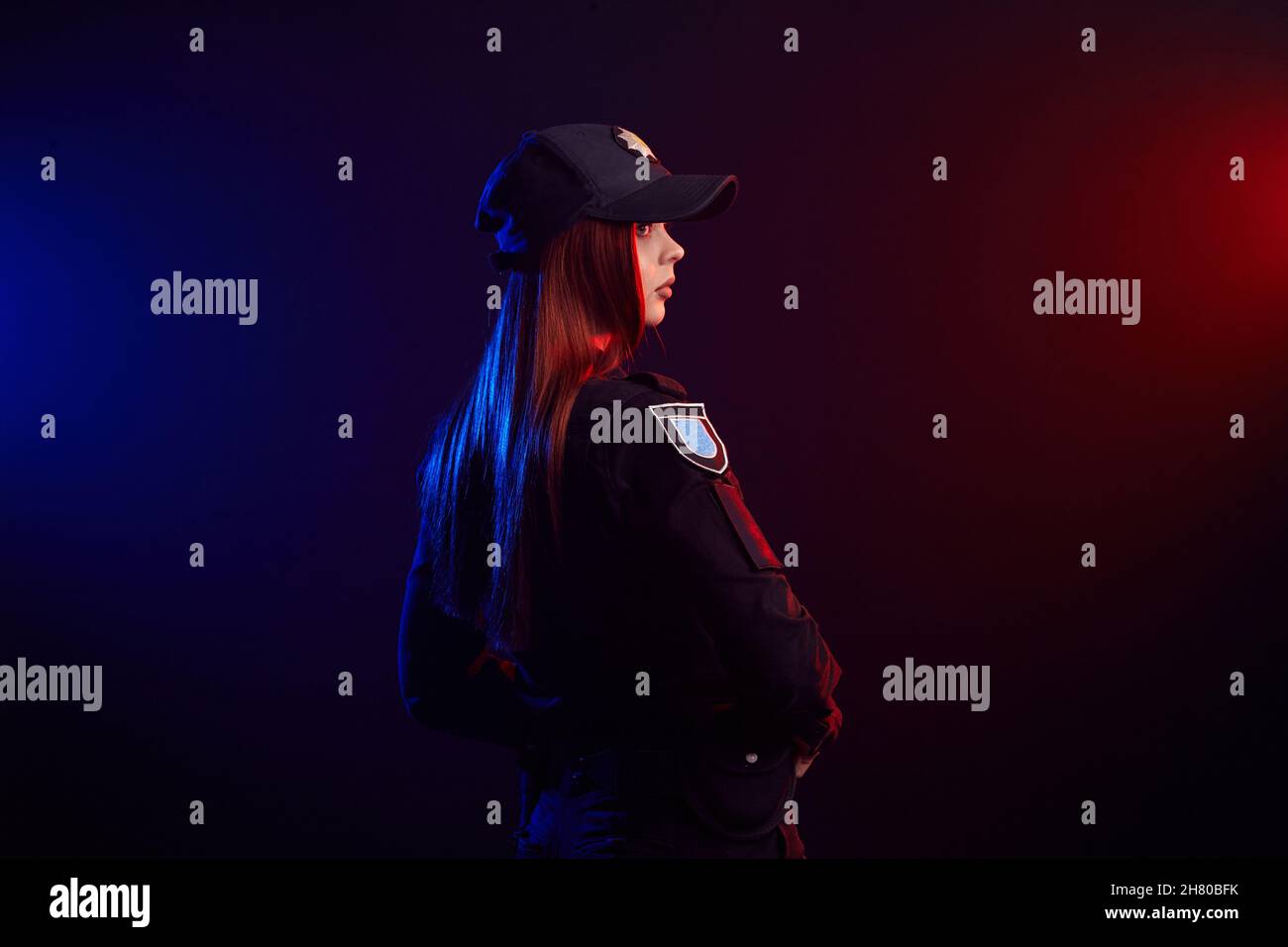 Serious female police officer is posing for the camera against a black ...