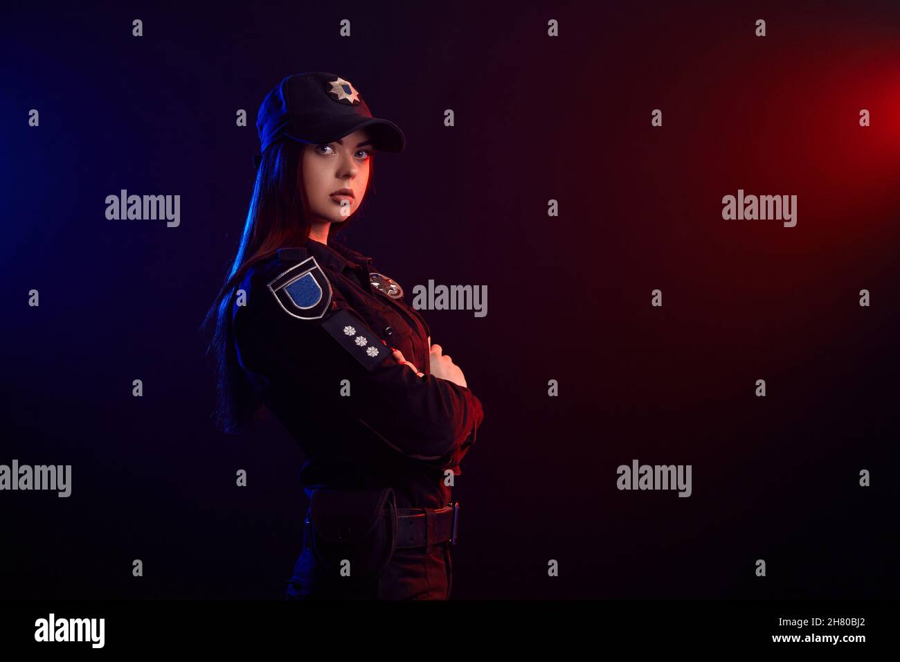 Serious female police officer is posing for the camera against a black ...