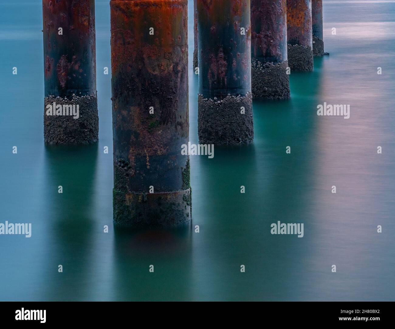 rusting and corroded metal piles on an old pier, abstract of sea and ...