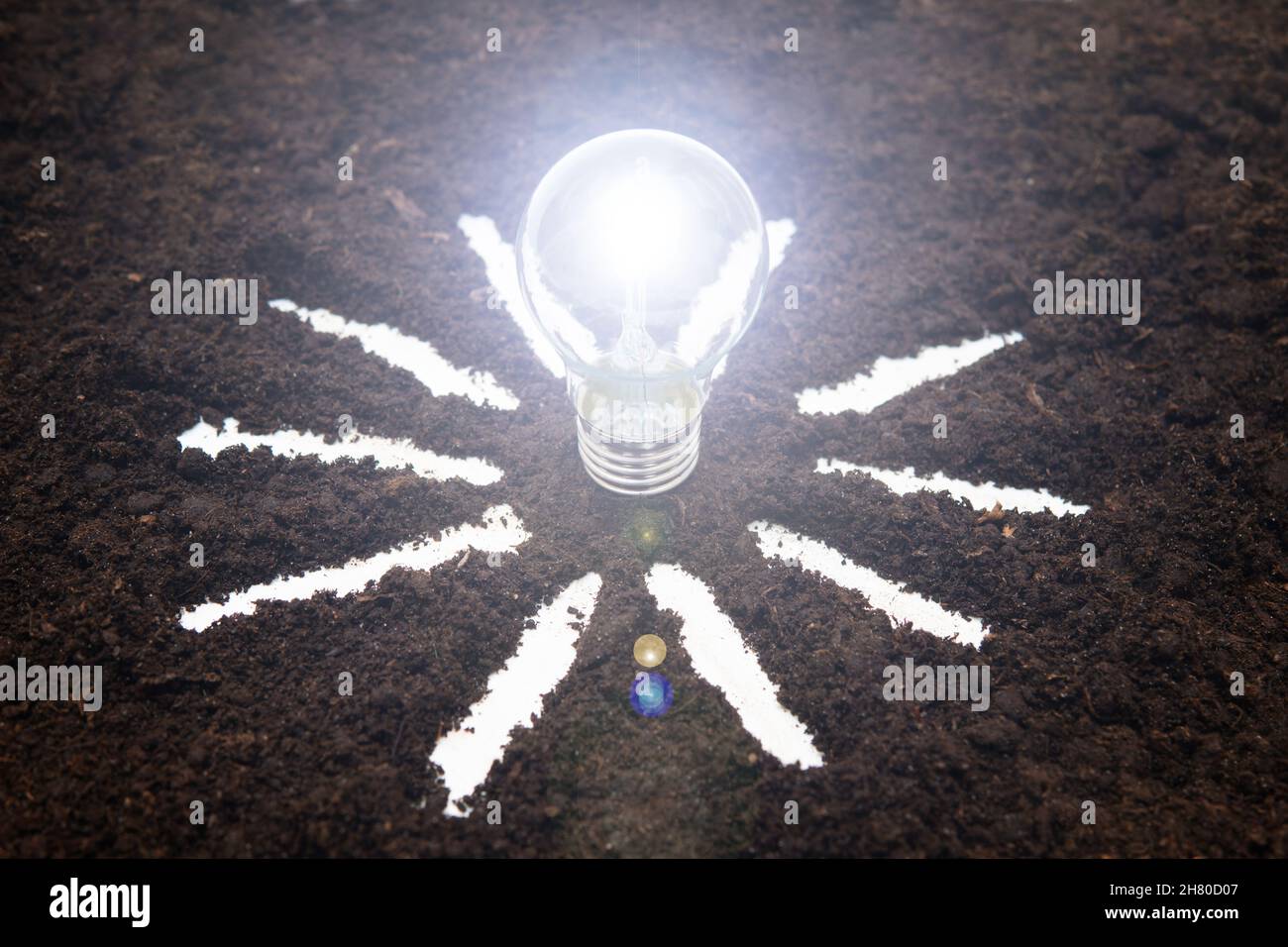 Glowing light bulb with a sun symbol on the soil. Solar power concept ...