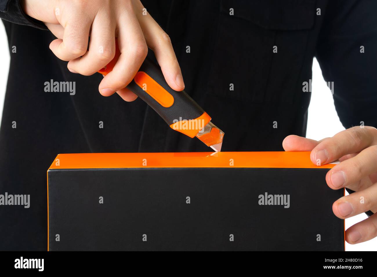 Man in black uniform using a retractable utility knife to open a sealed ...