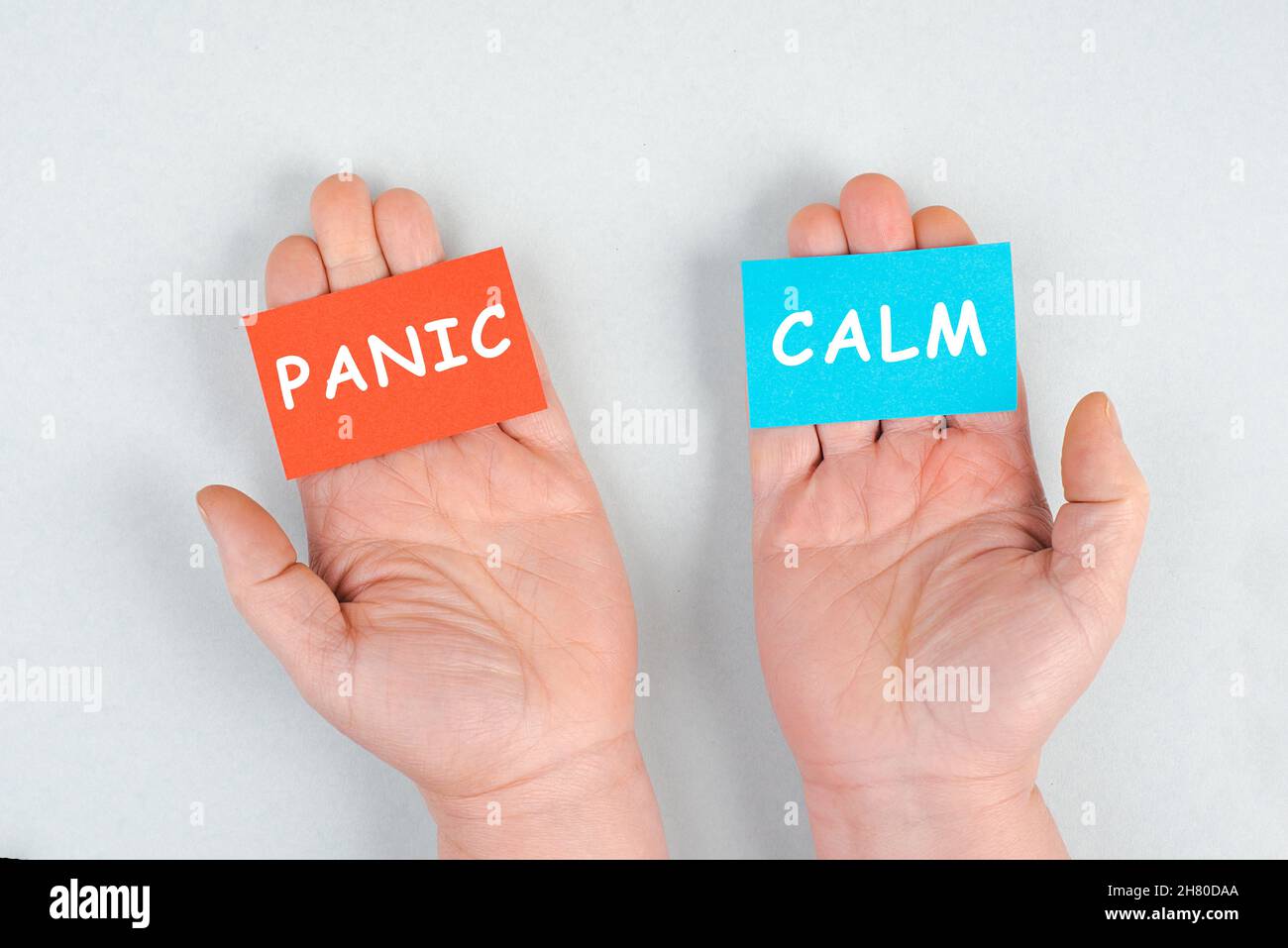 The words calm and panic are standing on pieces of paper, hands holding ...