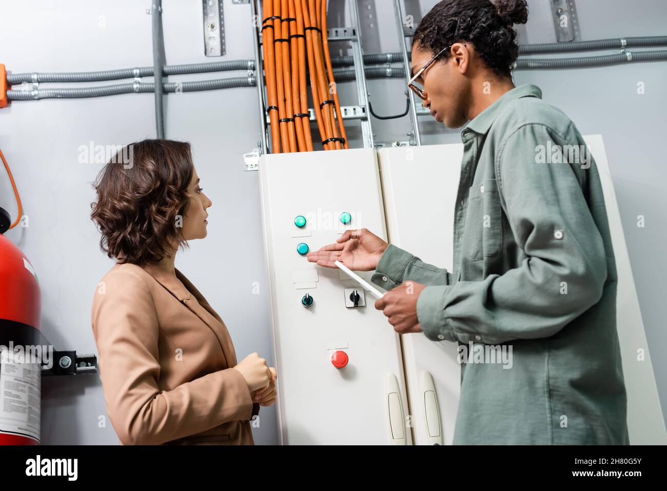 african american technician with digital tablet pointing at switchboard ...