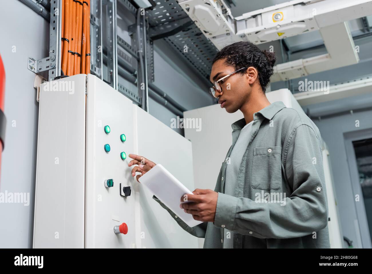 young african american technician with digital tablet pushing button on ...