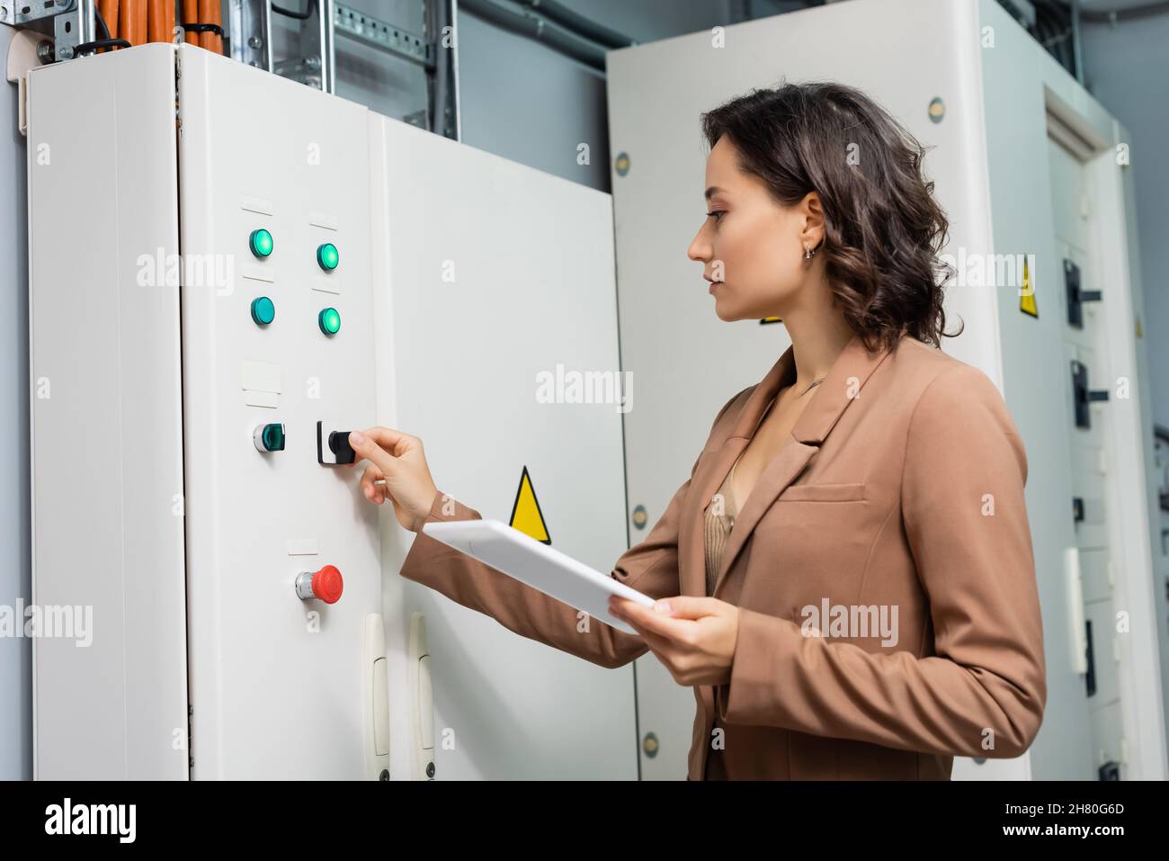 technician operating switchboard in data center while holding digital ...