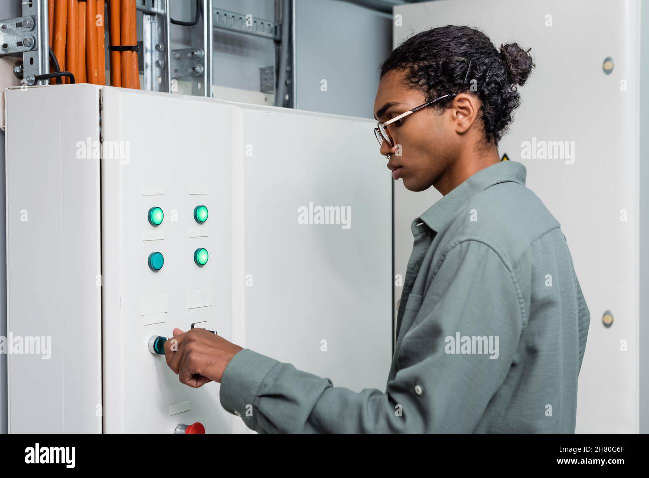 young african american technician pushing button on switchboard while ...