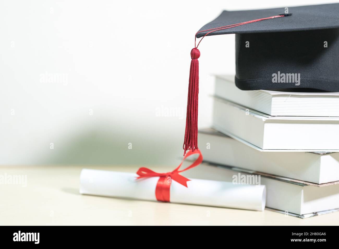 Closeup shot of a certificate, and a mortarboard on a stack of books on ...