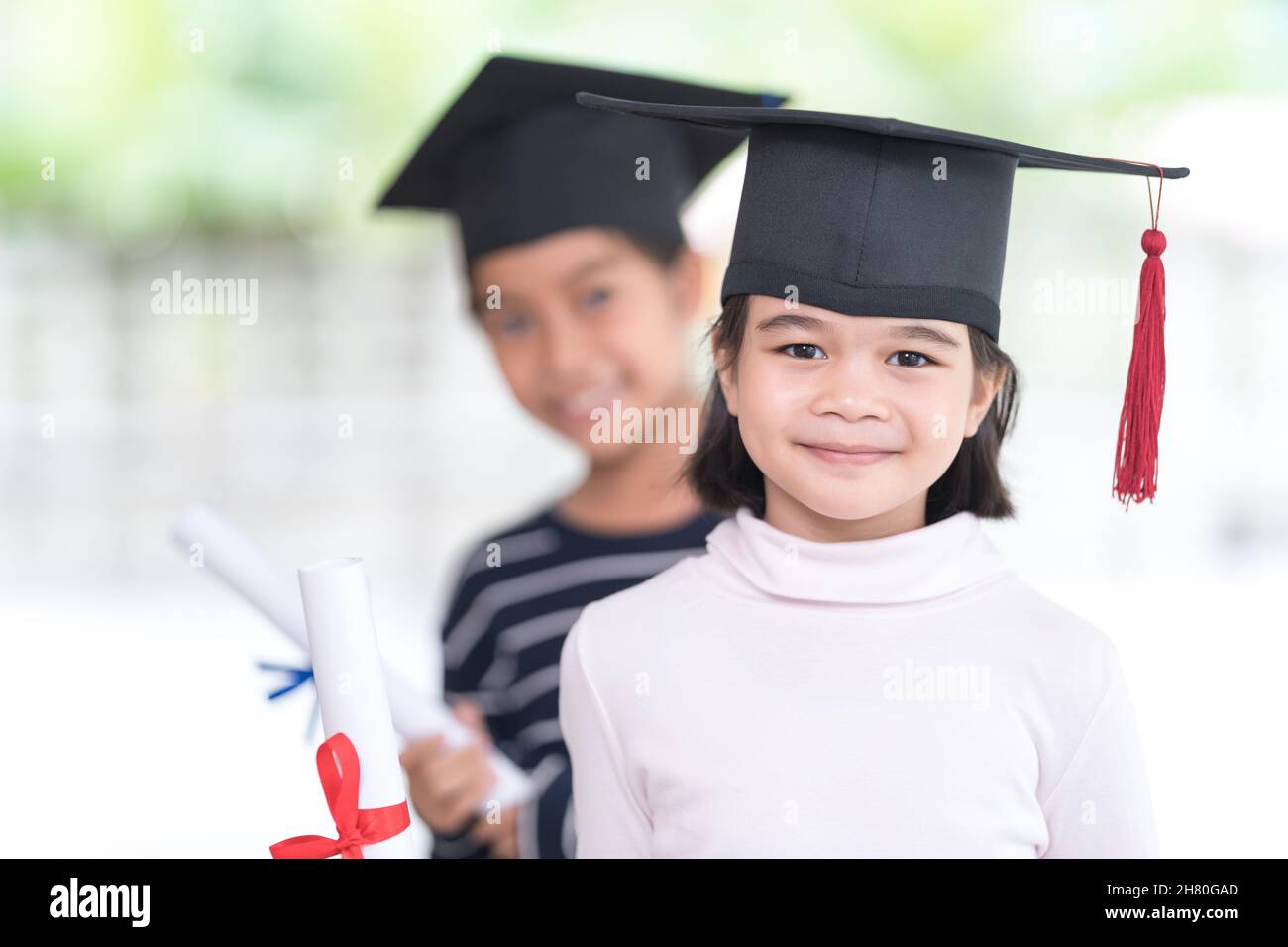 Graduation concept with two happy Southeast Asian schoolgirls with ...