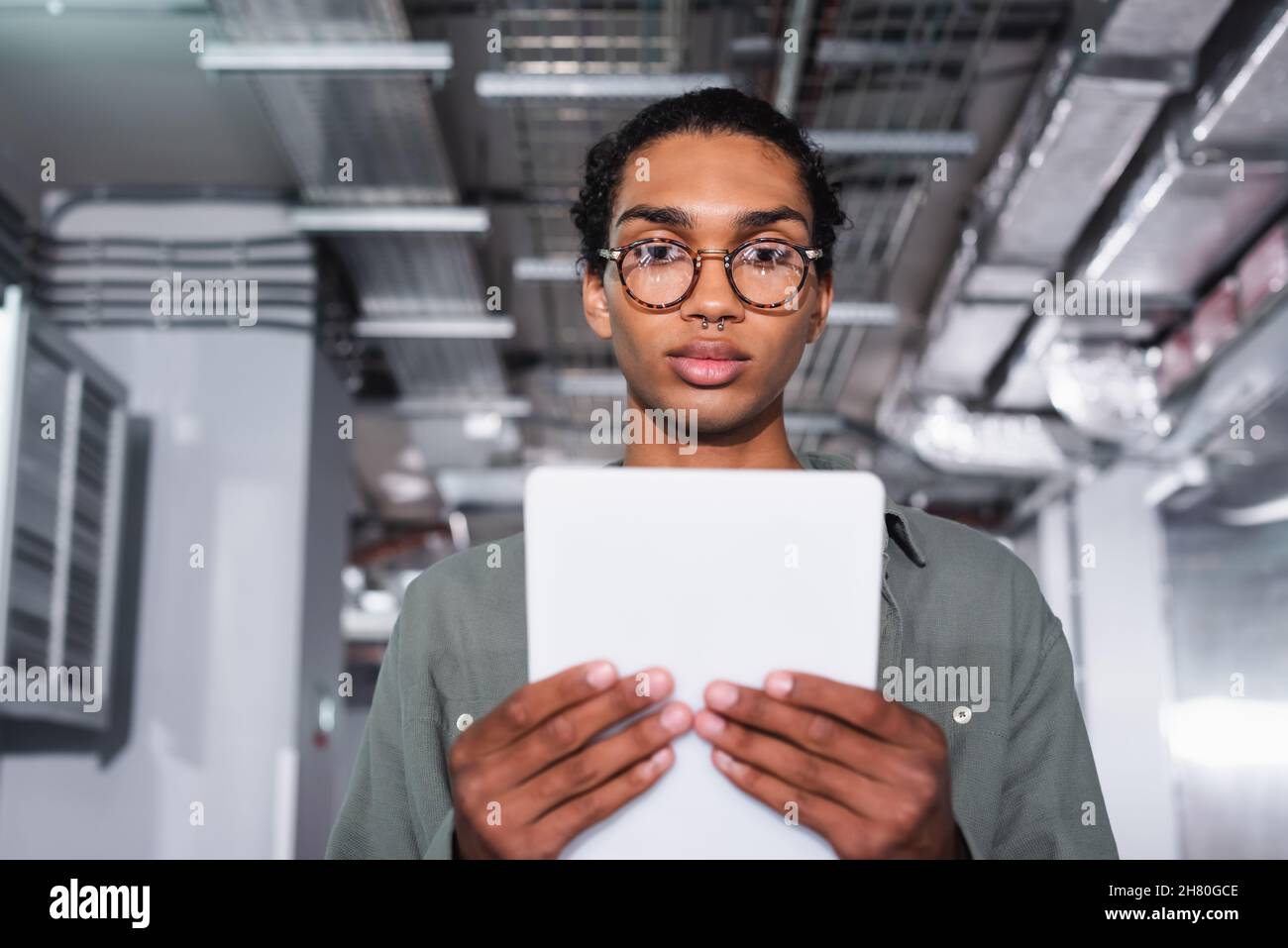 young african american programmer holding digital tablet while looking ...