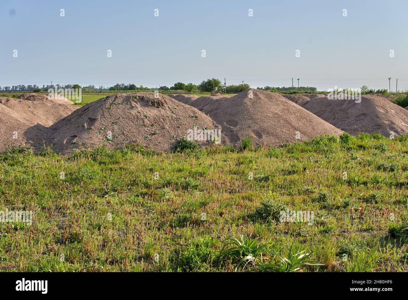 Pile of sand in green field Stock Photo - Alamy