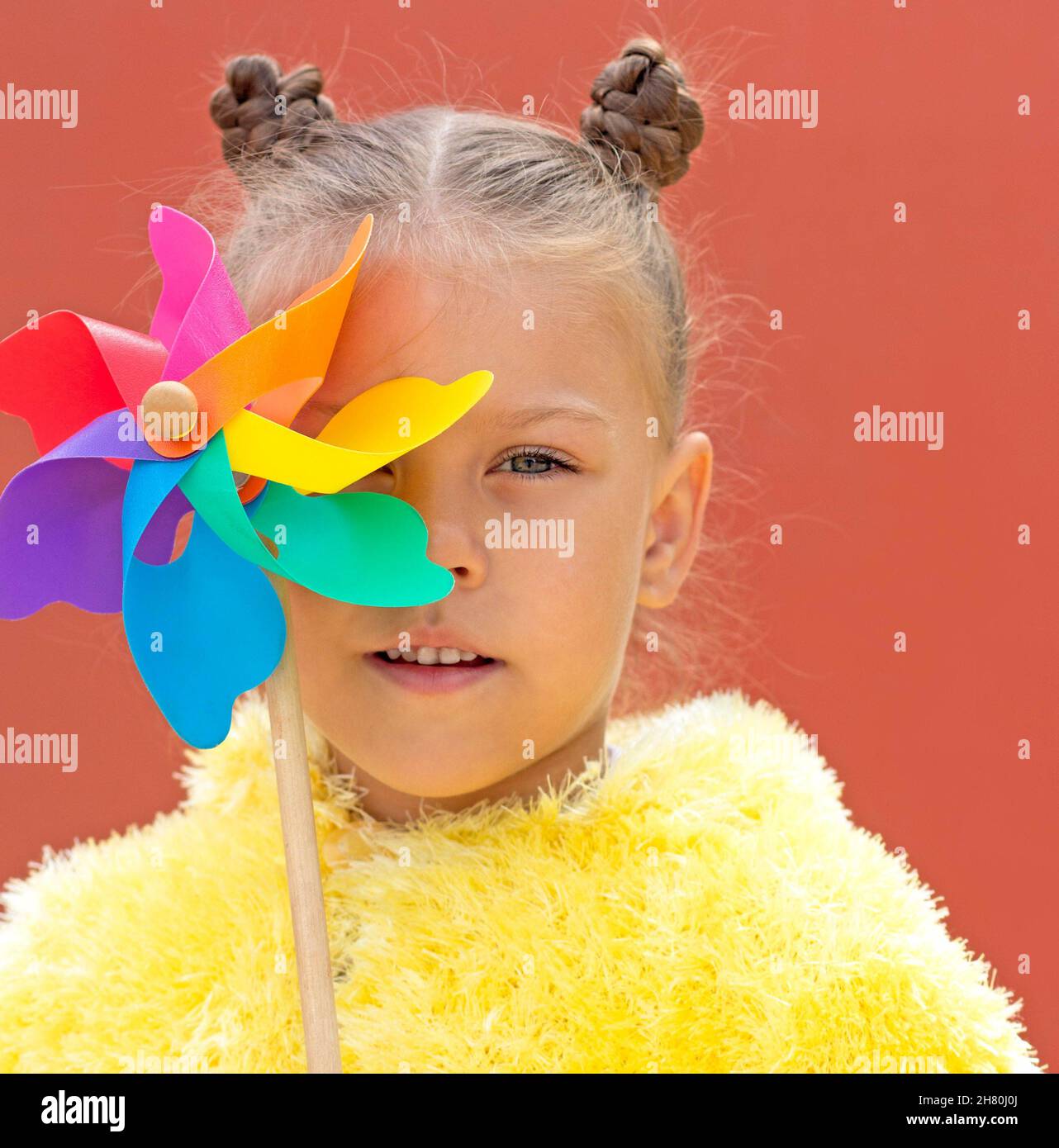 Caucasian little girl of 5 years holding pinwheel near face looking at ...