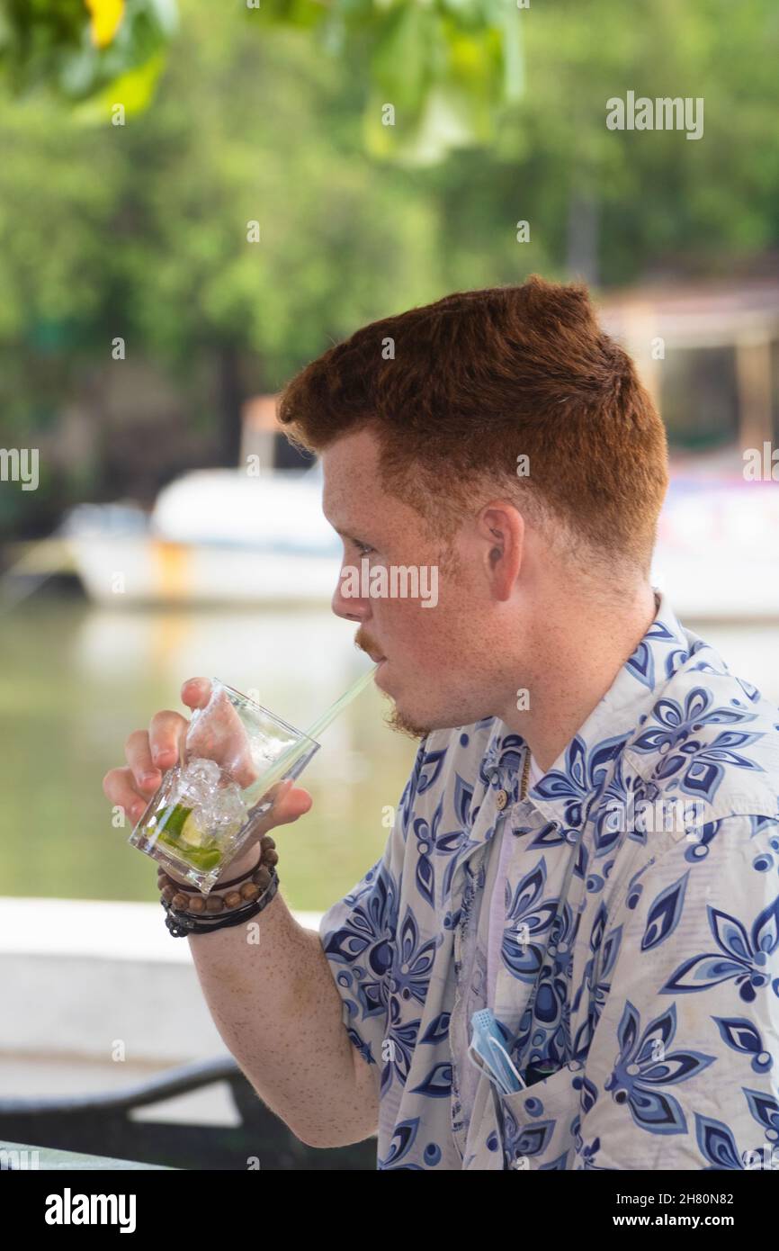 Vertical Closeup Portrait Of A Hispanic Guy Drinking Alcohol At A Cafe