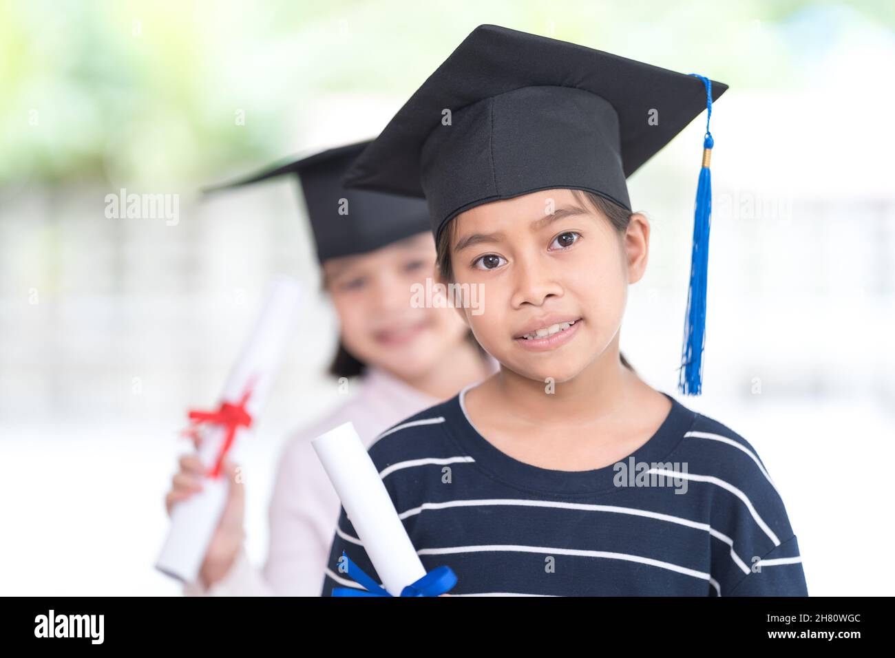 Graduation concept with two happy Southeast Asian friend schoolgirls ...