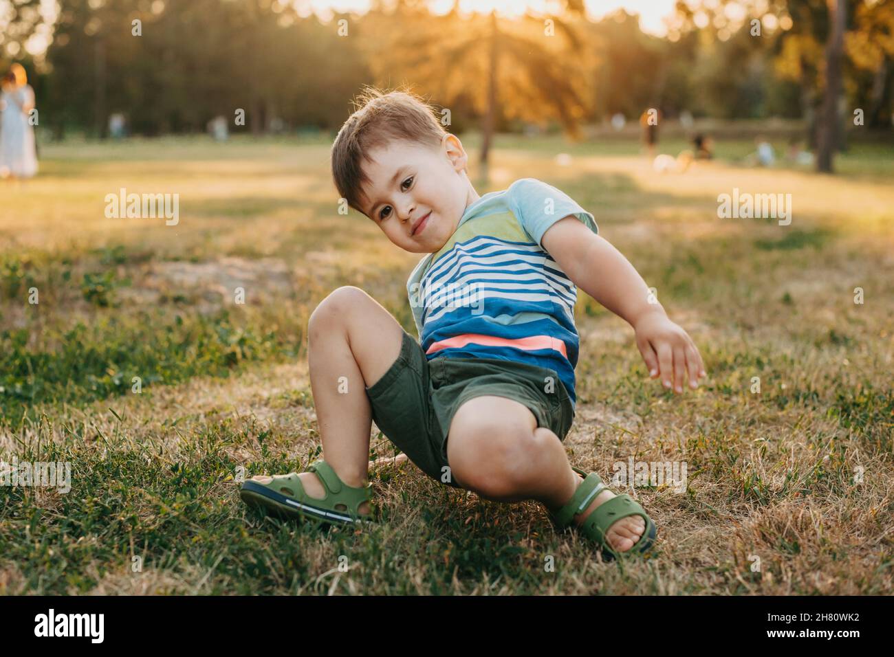 Portrait of a boy trying to get up after falling down in the park ...