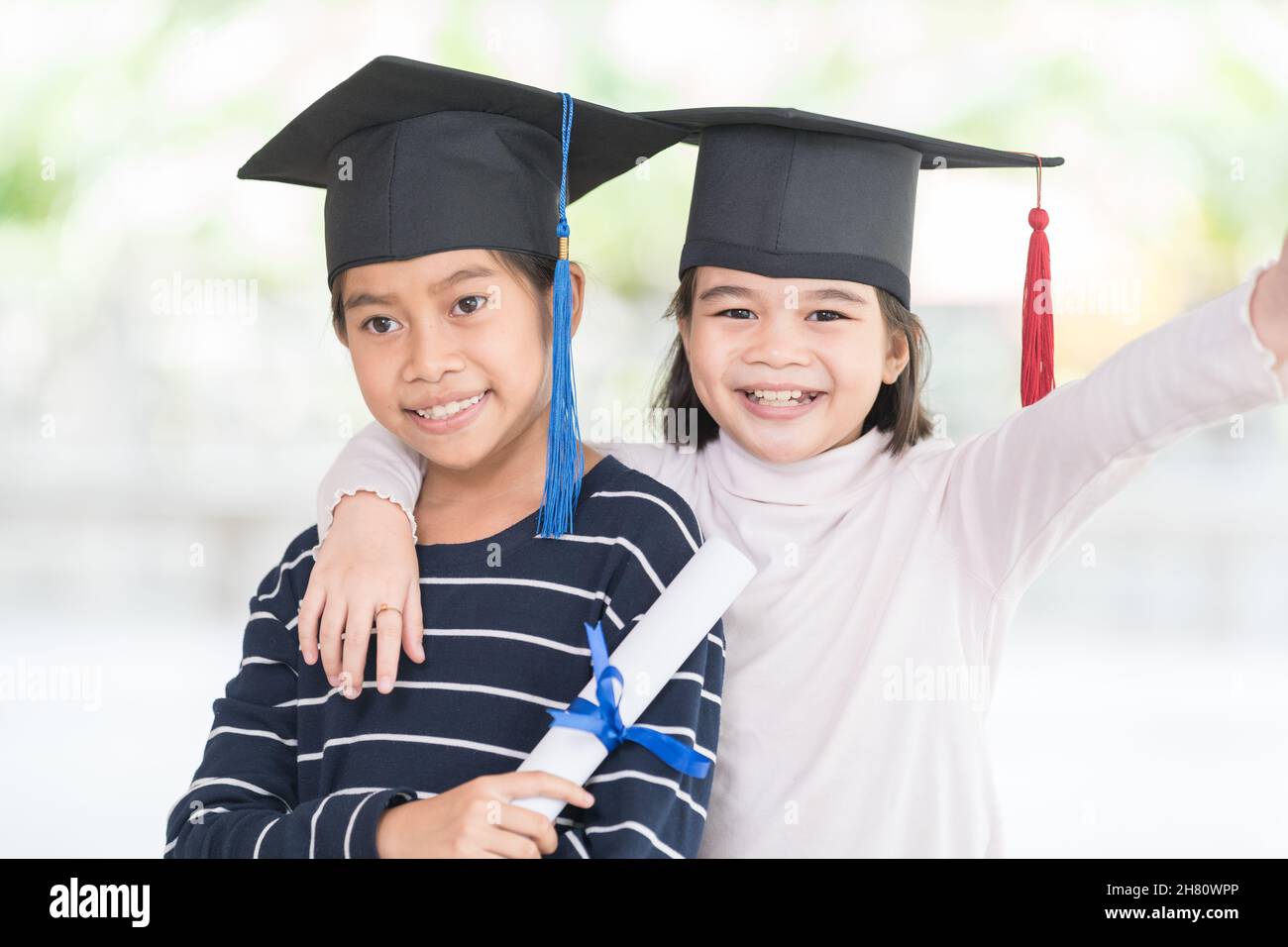 Graduation concept with two happy Southeast Asian friend schoolgirls ...