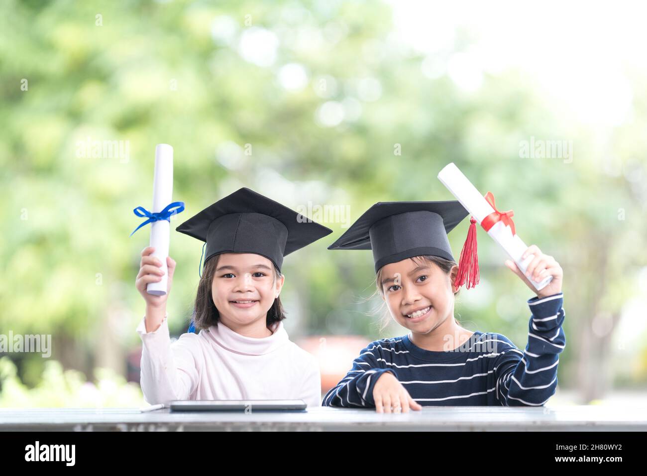 Graduation concept with two happy Southeast Asian friend schoolgirls ...