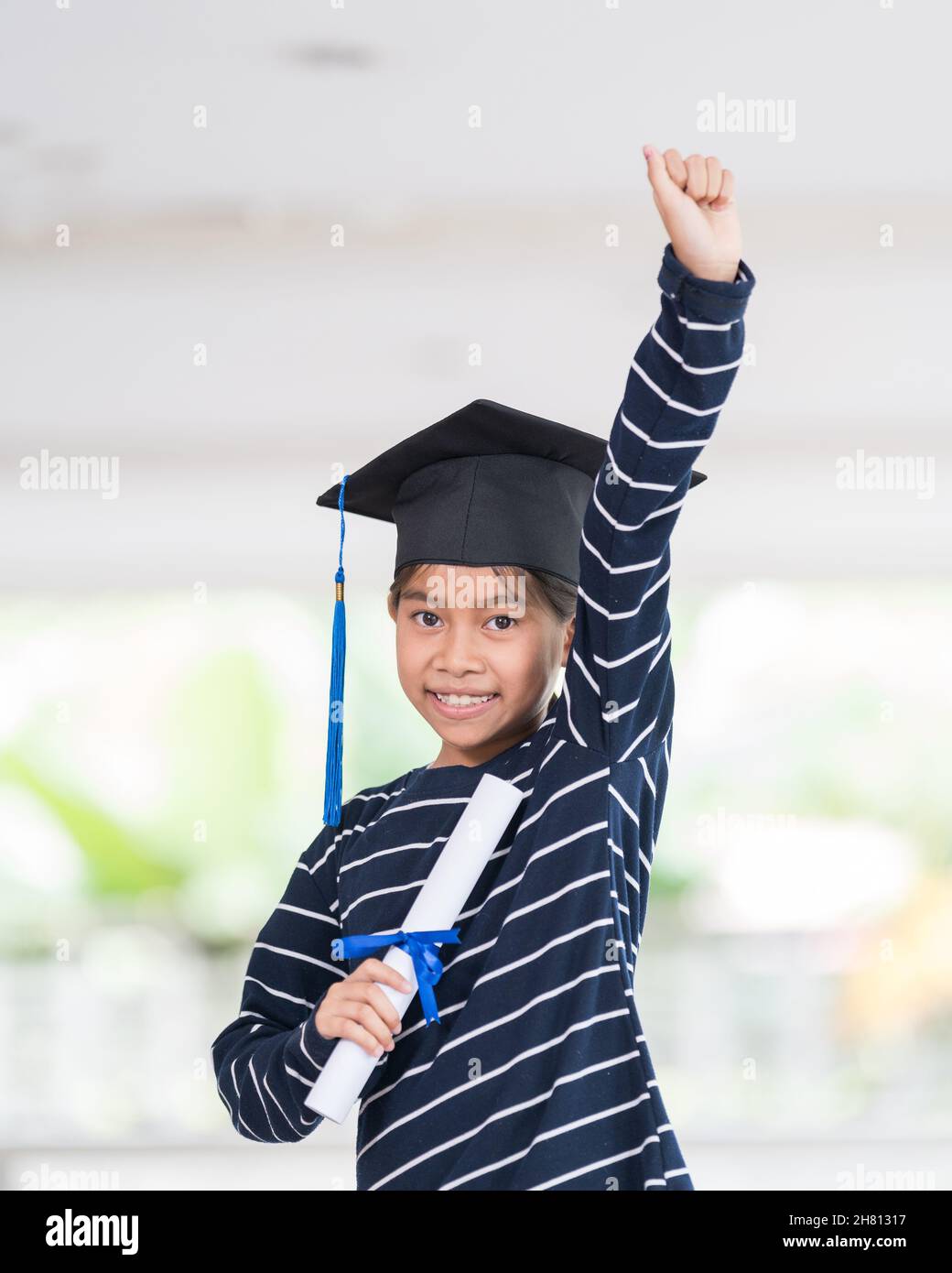 Shallow focus shot of a happy Thai kid with a graduation hat and ...