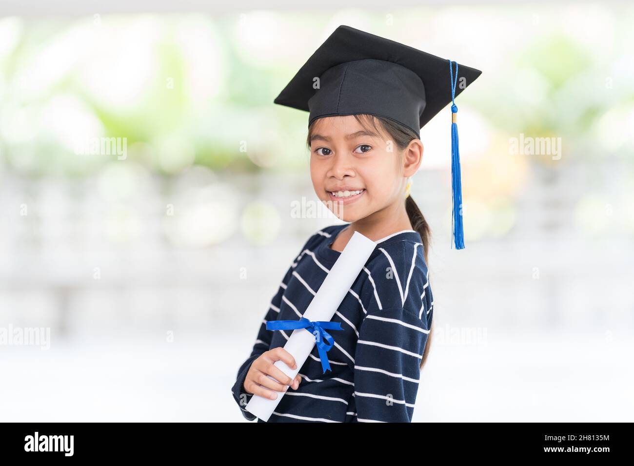 Shallow focus shot of a happy Thai kid with a graduation hat and ...