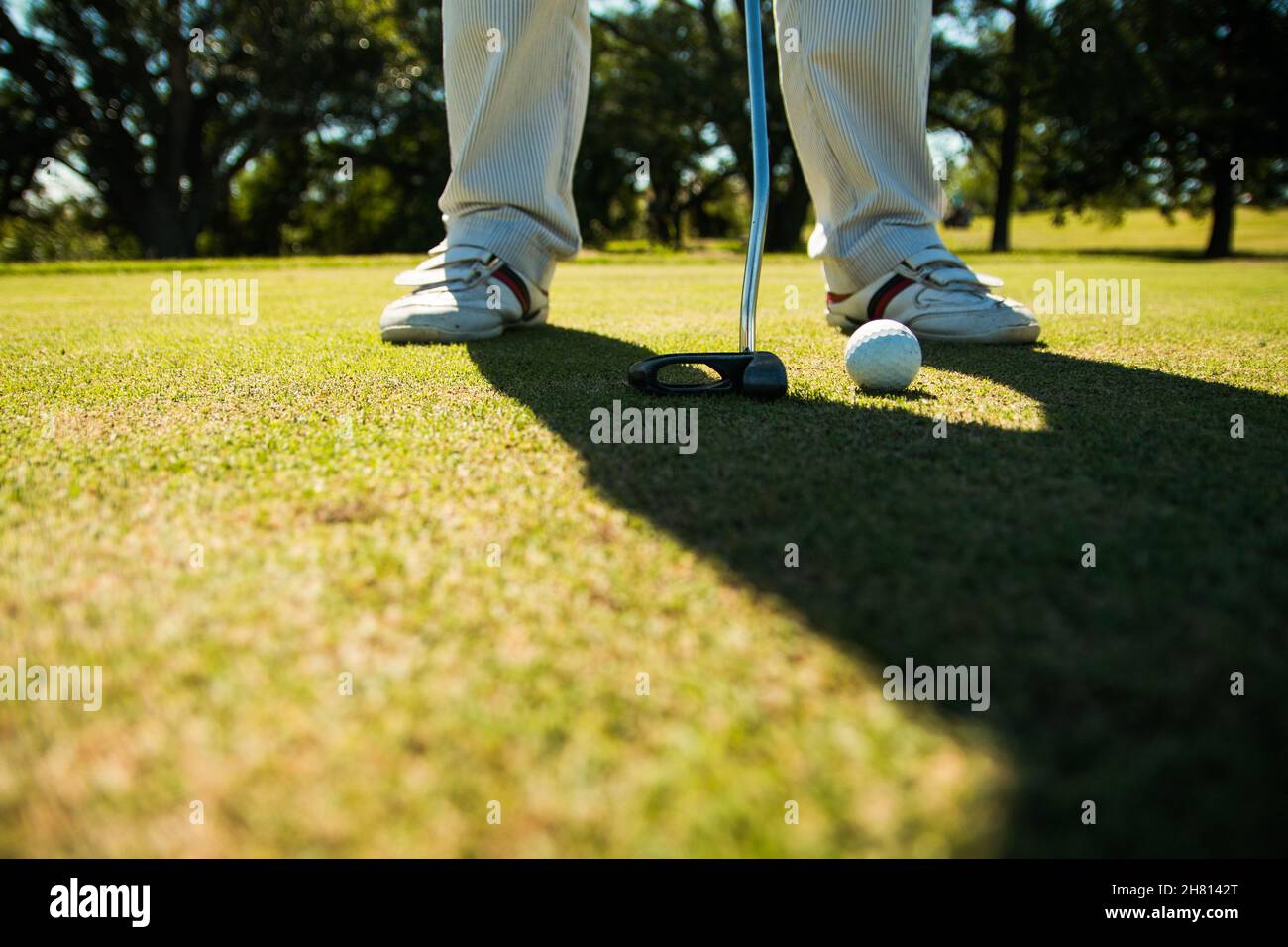 Shot of a golfer's feet on the hole grass with ball, getting ready to ...