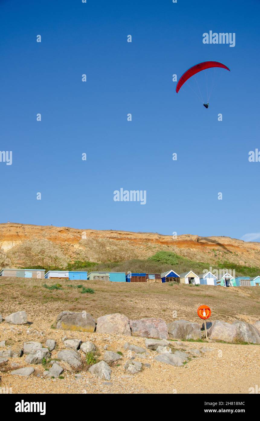 Paraglider above cliffs and beach huts at Barton on Sea, Hampshire ...
