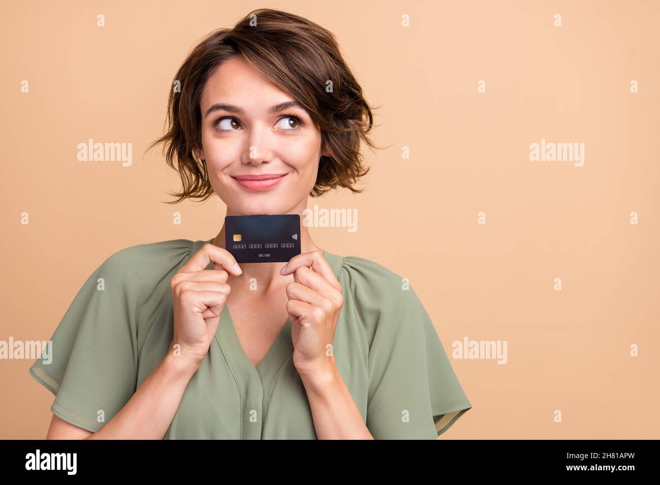 Photo of cheerful dreamy girlish lady hold debit card look empty space ...