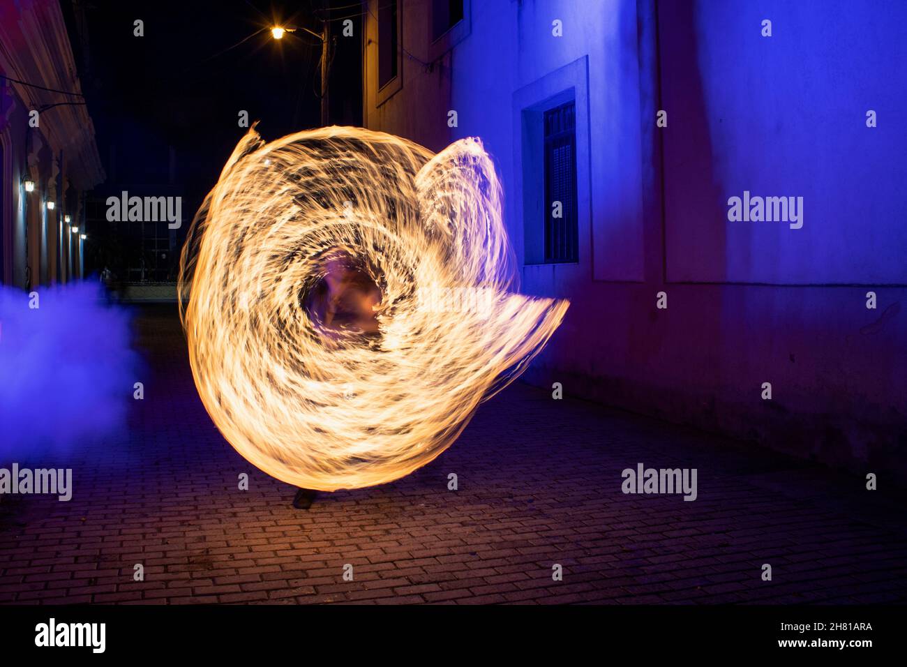 Fire show with spiral shapes in an area under purple lighting at night ...