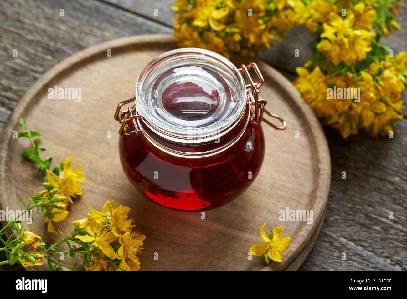 A jar of red oil made from St. John's wort flowers with fresh Hypericum ...