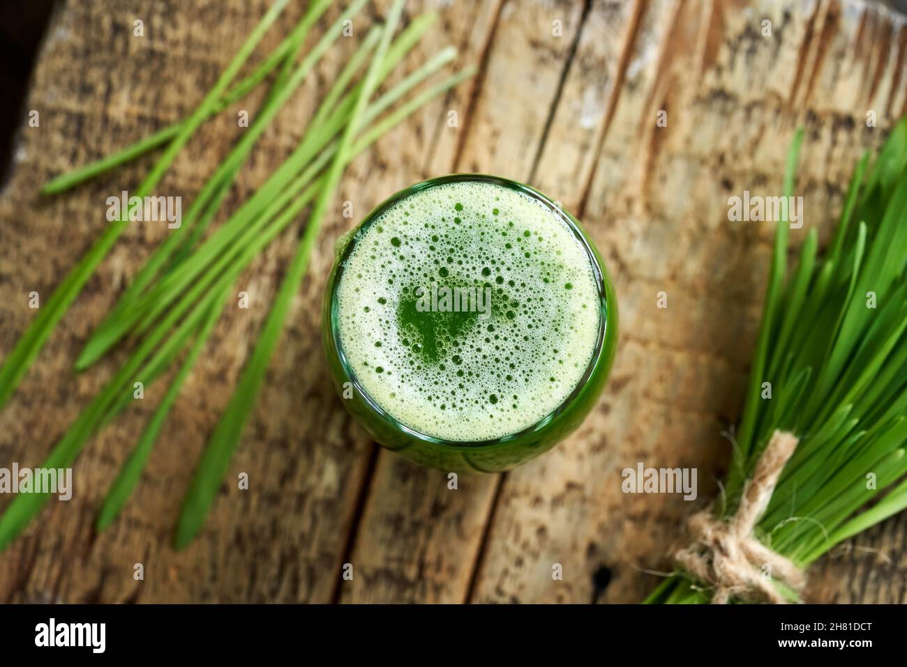 A glass of healthy green barley grass juice, with fresh barleygrass in ...