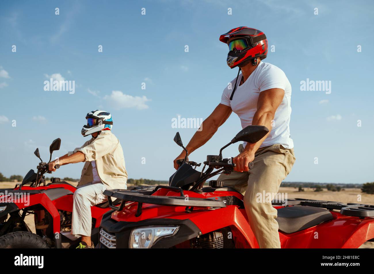 Men in helmets and glasses ride on atv in desert Stock Photo - Alamy