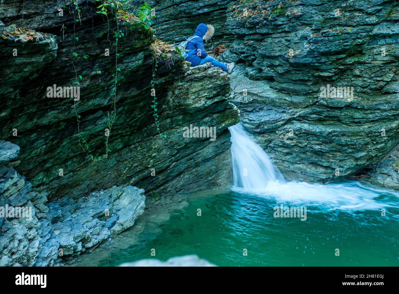 Hiker looking at the small waterfalls of the Rui stream, Mel, Belluno ...