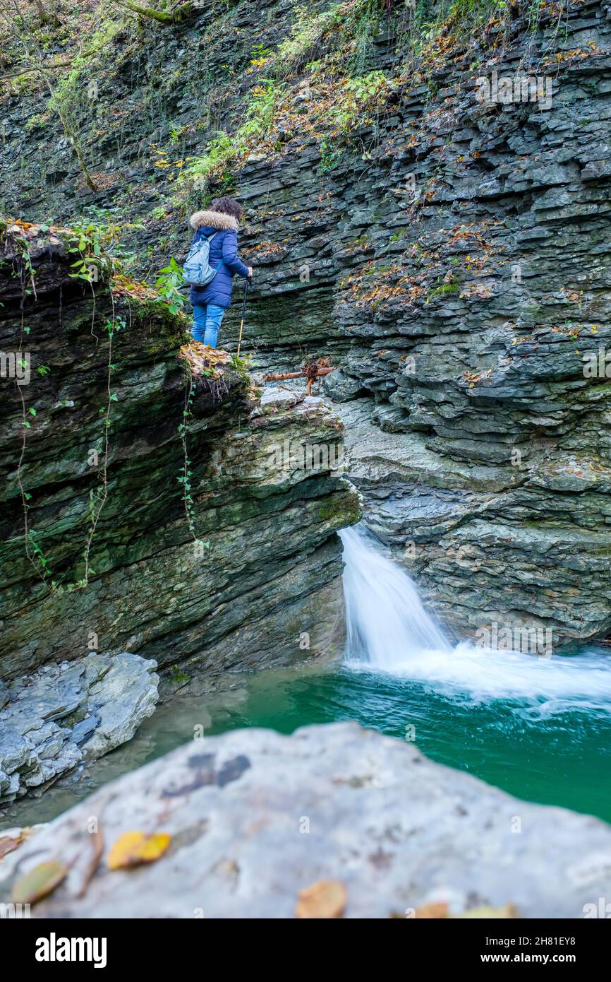 Hiker looking at the small waterfalls of the Rui stream, Mel, Belluno ...