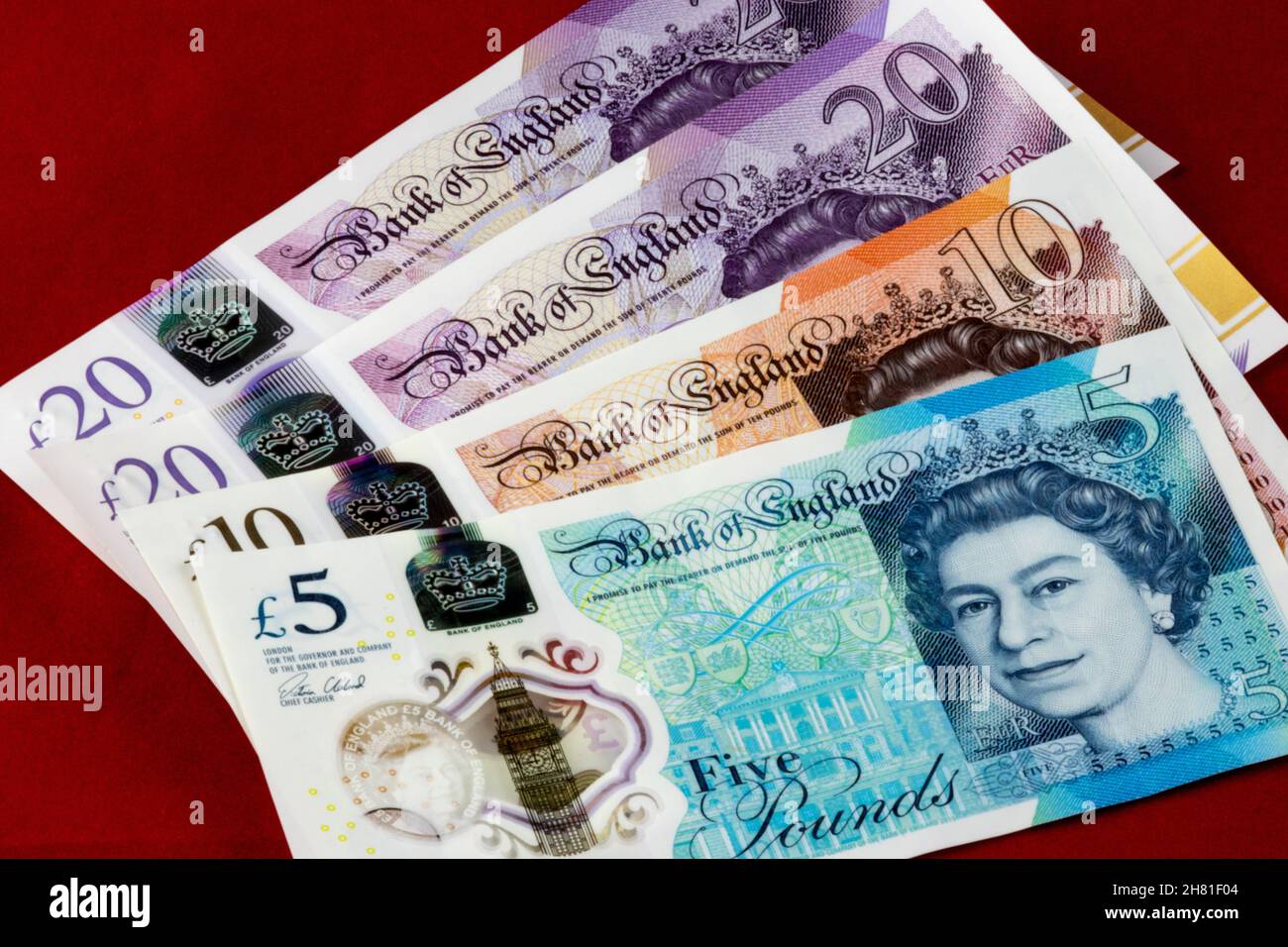 Assorted bank of England banknotes on a red background Stock Photo - Alamy