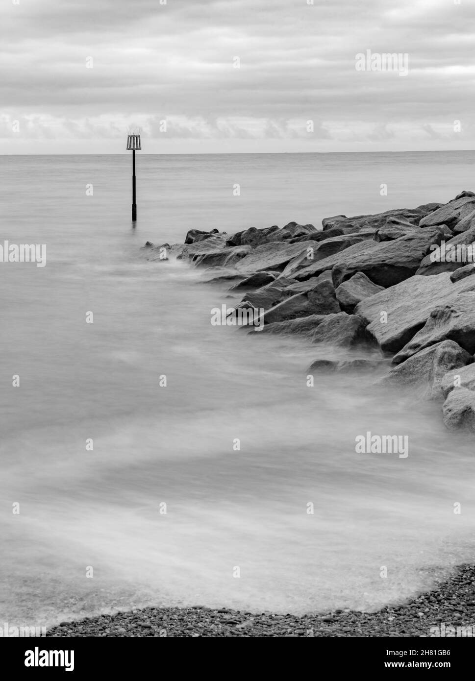 Black and white picture of marker bouy against rocks in the sea at ...