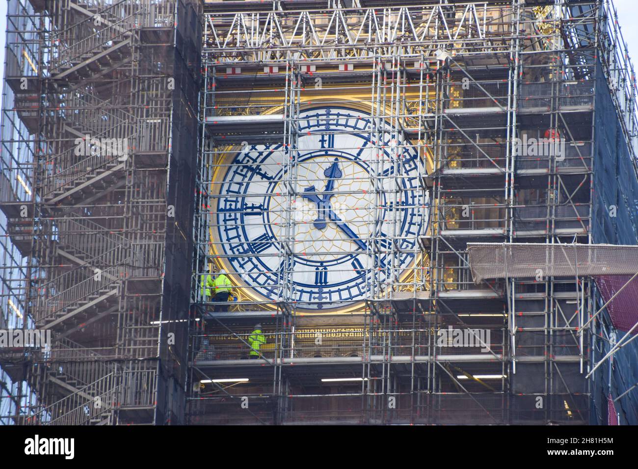 London, UK. 26th November 2021. Workers renovate the clock face as ...
