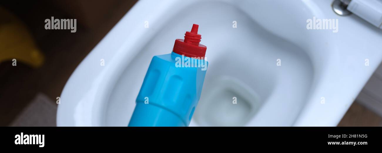 Cleaner in yellow rubber gloves pouring detergent under rim of toilet ...