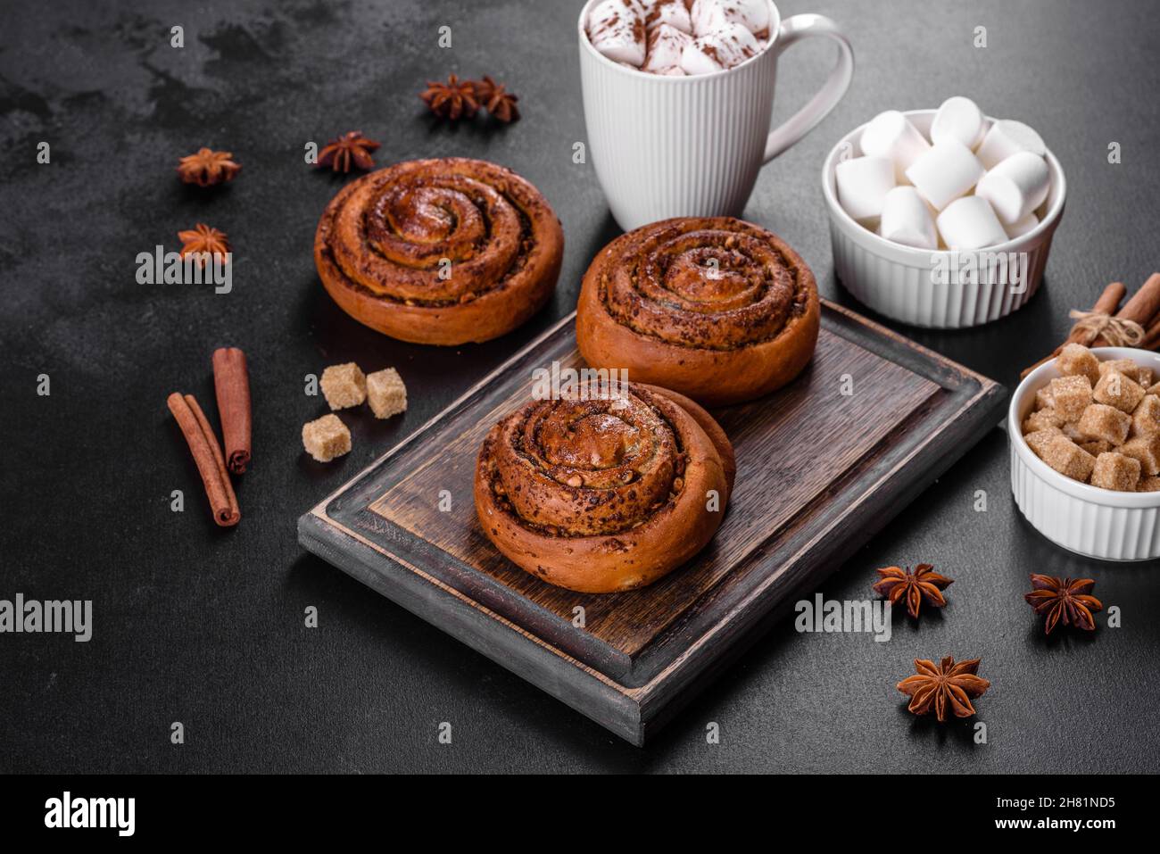 Freshly baked cinnamon roll with spices and cocoa filling on a black ...