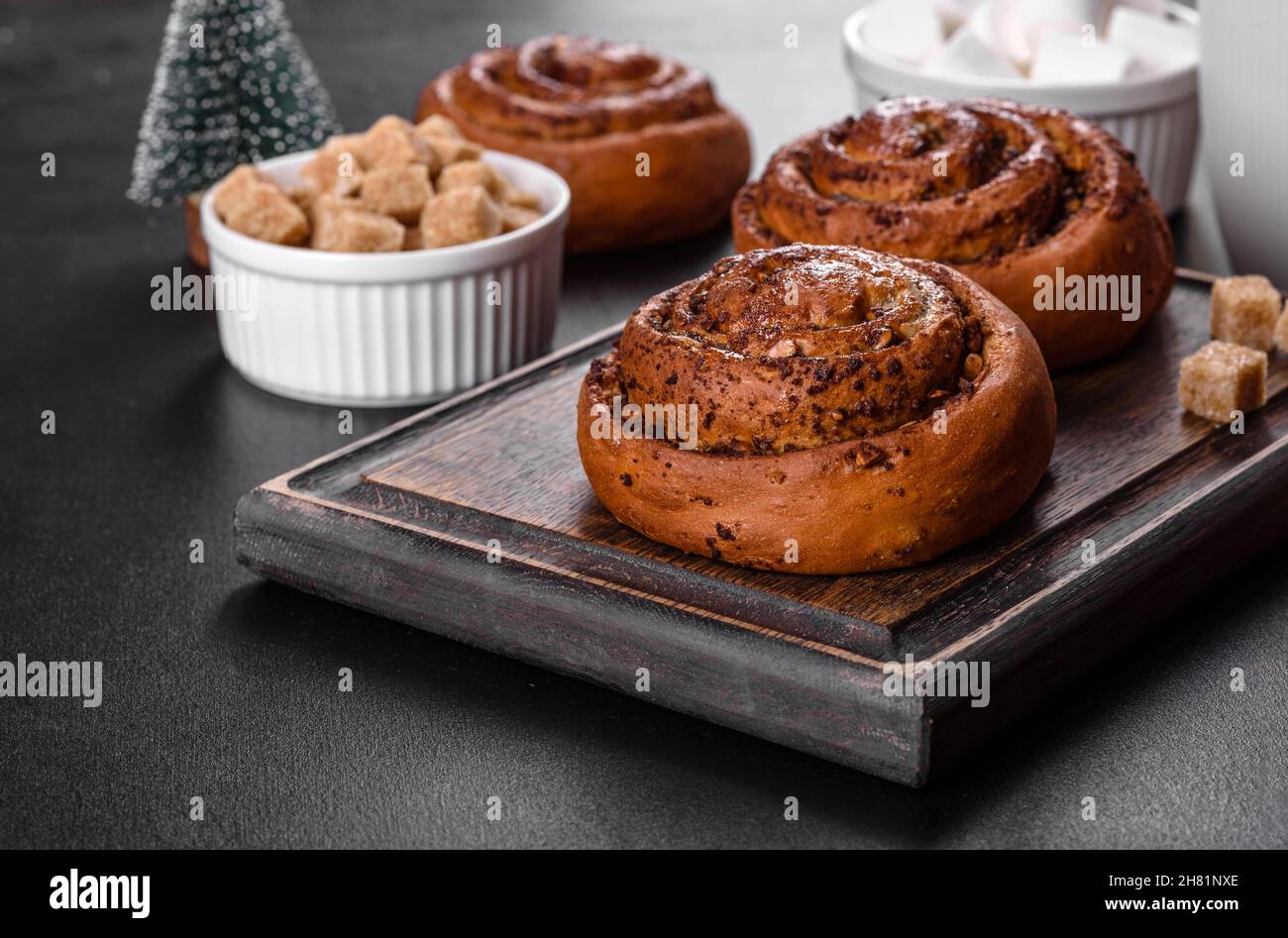 Freshly baked cinnamon roll with spices and cocoa filling on a black ...