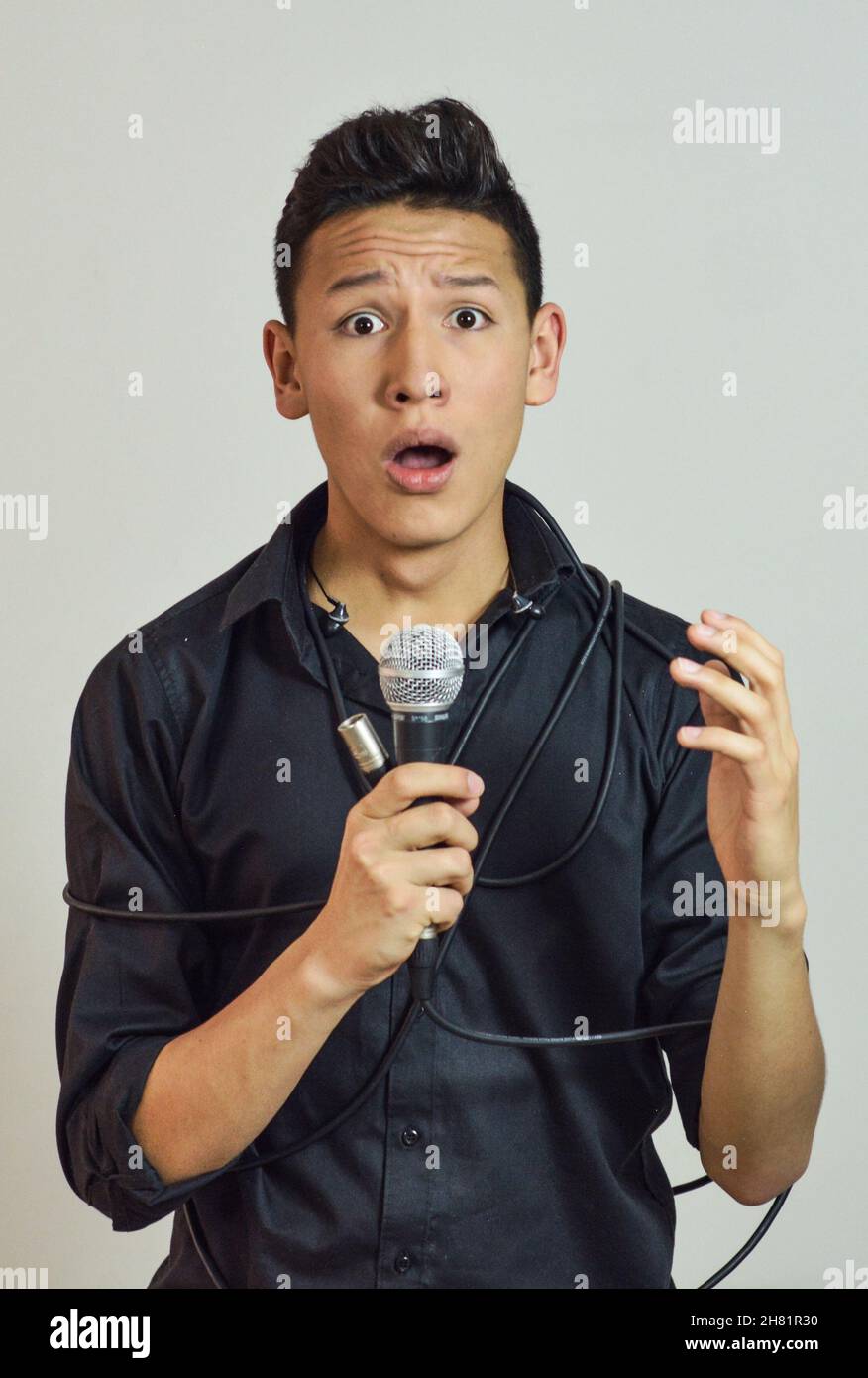 Vertical shot of a scared Colombian male trapped with microphone wires ...