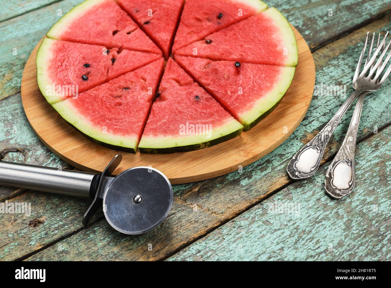 Fresh juicy organic watermelon cut in eight segments with pizza knife ...