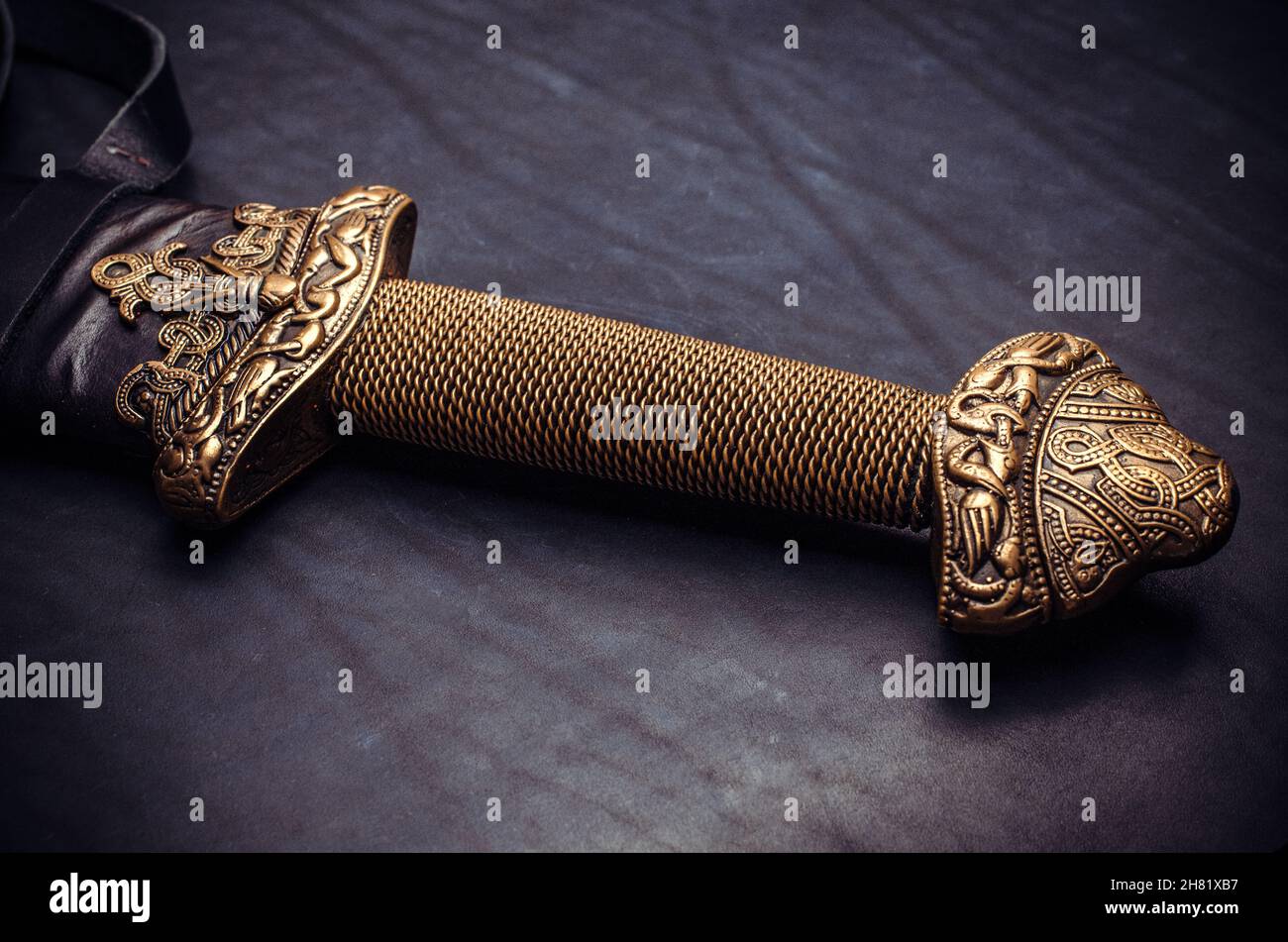 The hilt of the sword in a bronze sheath on a black background Stock ...