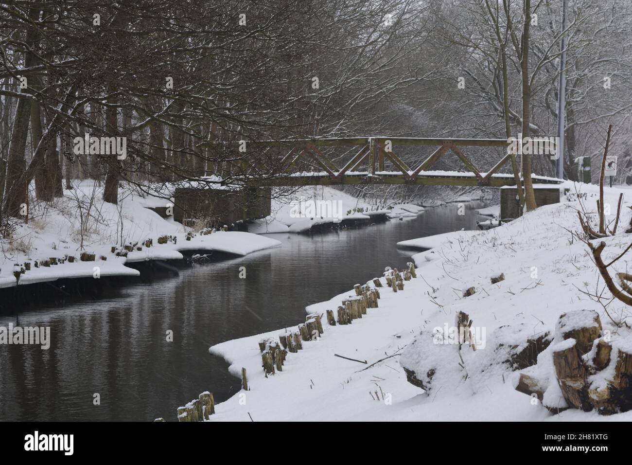 Beautiful snowy view of a wooden bridge above the river with ice on the ...