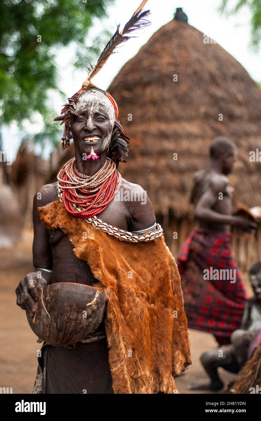 Karo woman in her village with a tall feather in her hair and a pink ...