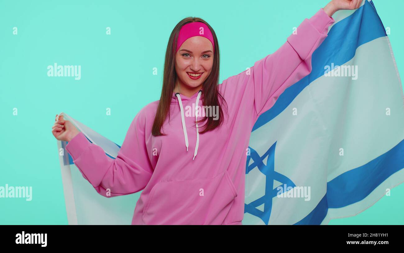 Cheerful lovely teen girl waving and wrapping in Israel national flag ...